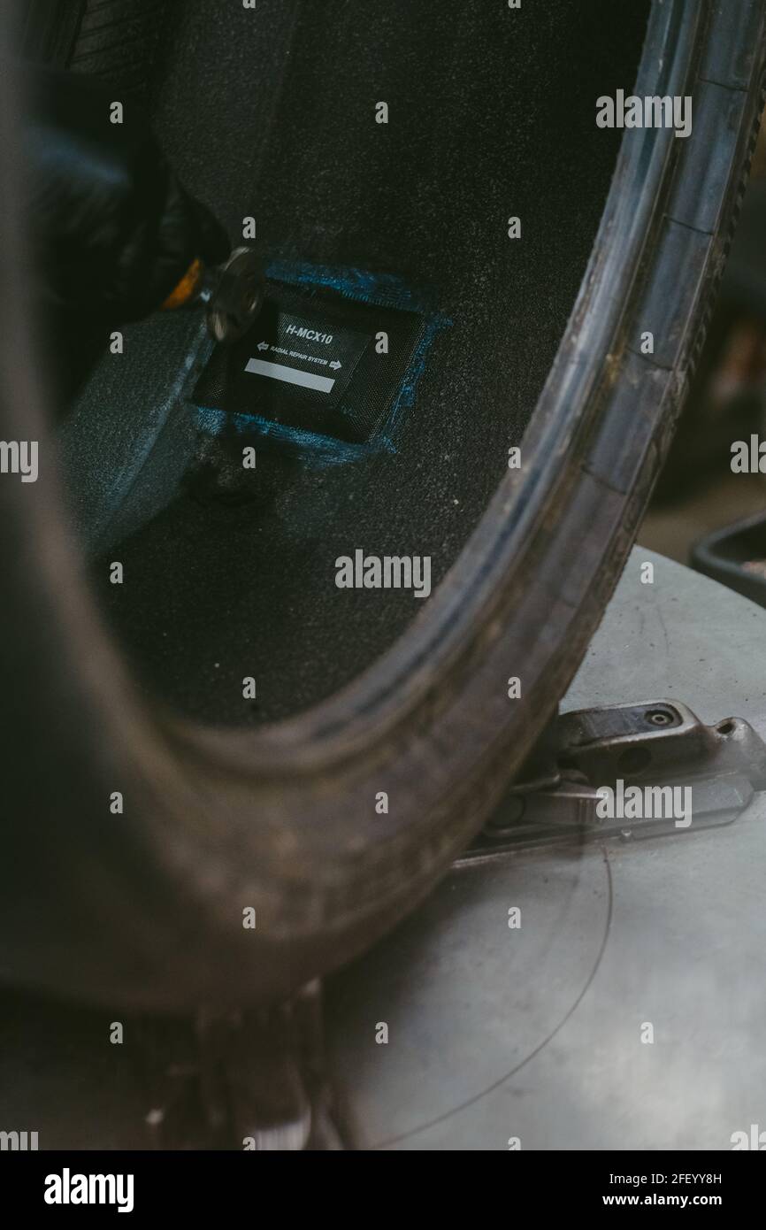 Vertical shot of a car tire missing its rim with a radial patch being ...