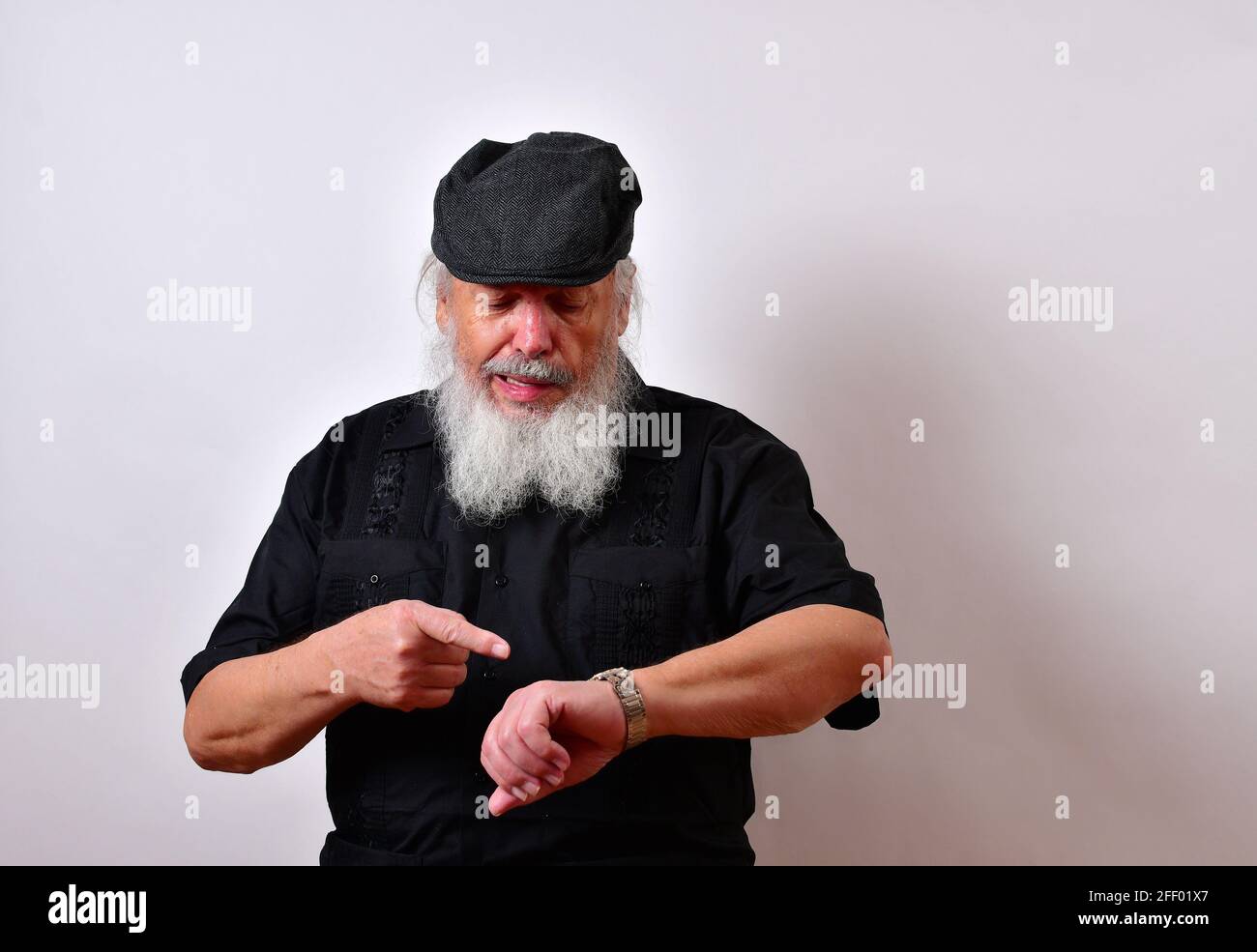 View of an elderly man poiting at his watch standing on a white ...