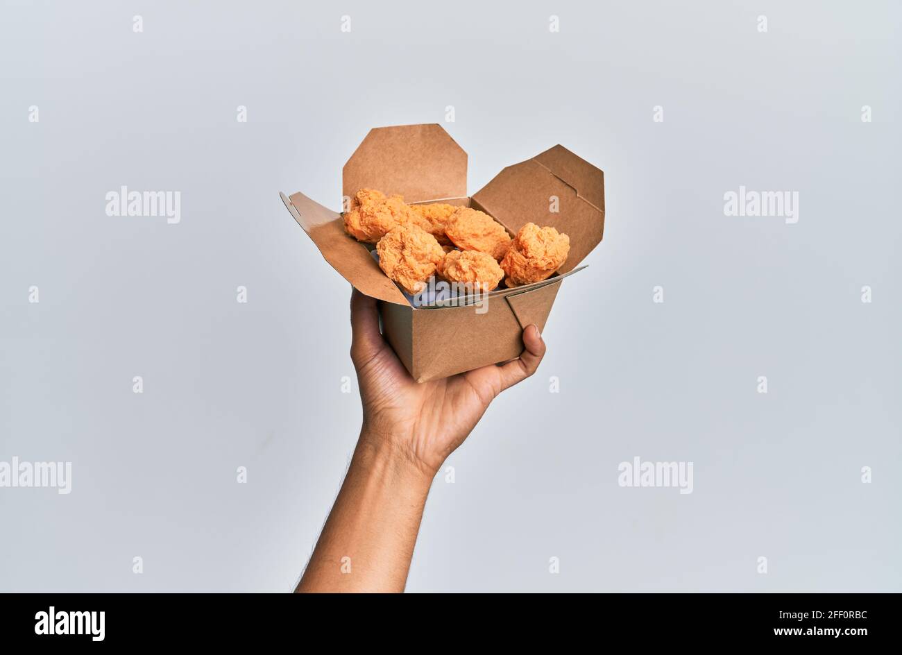 Hand of hispanic man holding fried chicken over isolated white ...