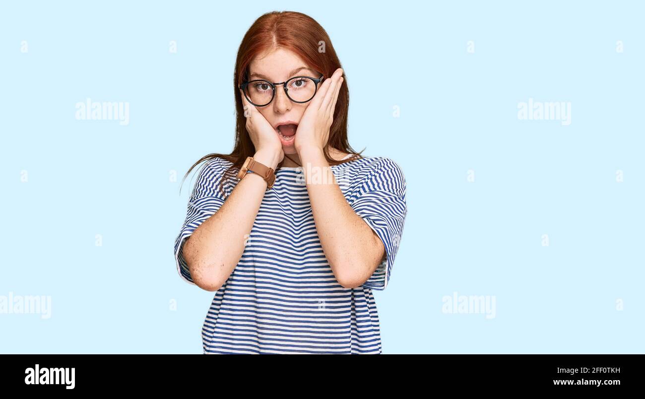 Young read head woman wearing casual clothes and glasses afraid and ...