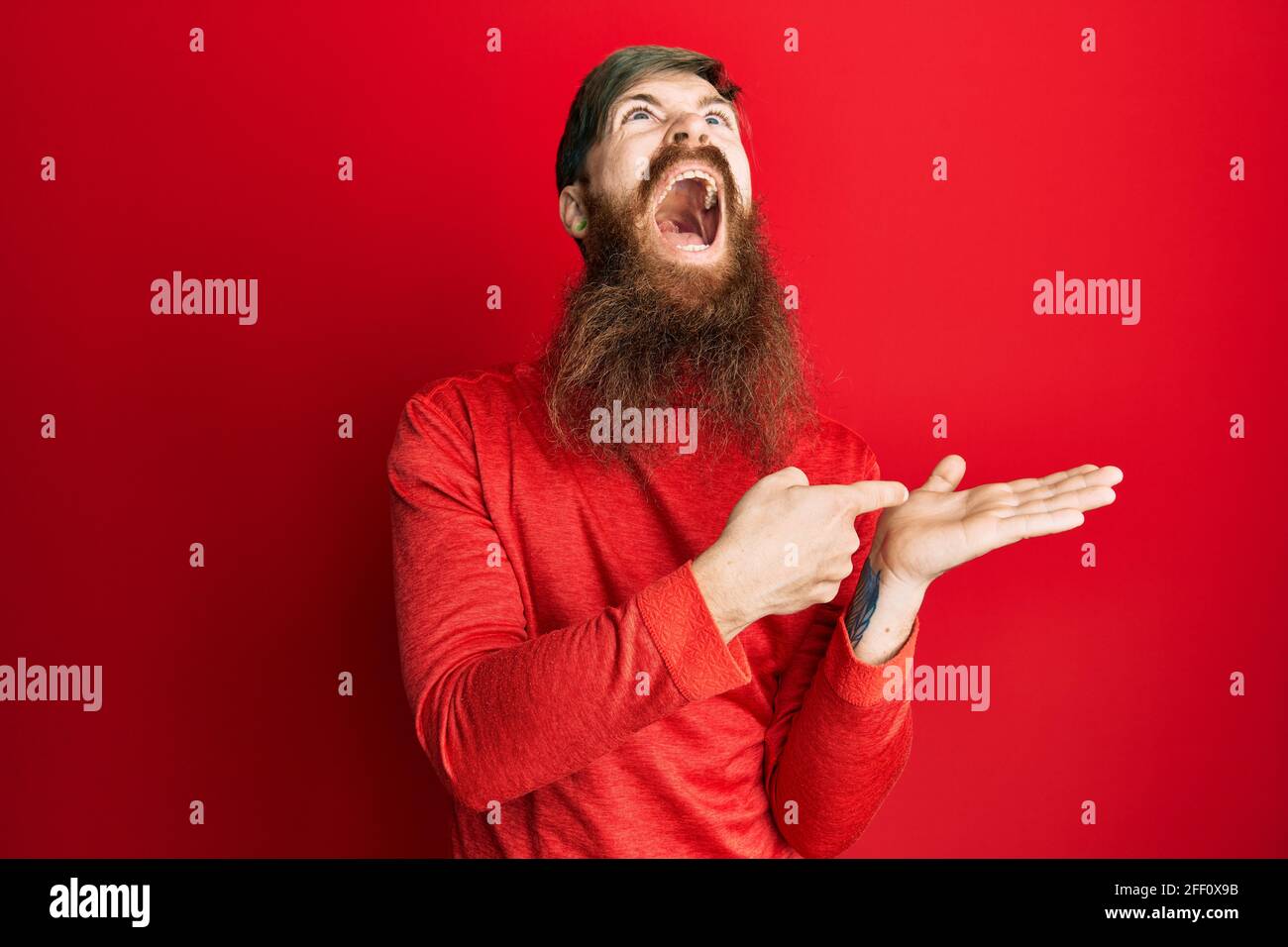 Redhead man with long beard pointing open palm with finger angry and ...
