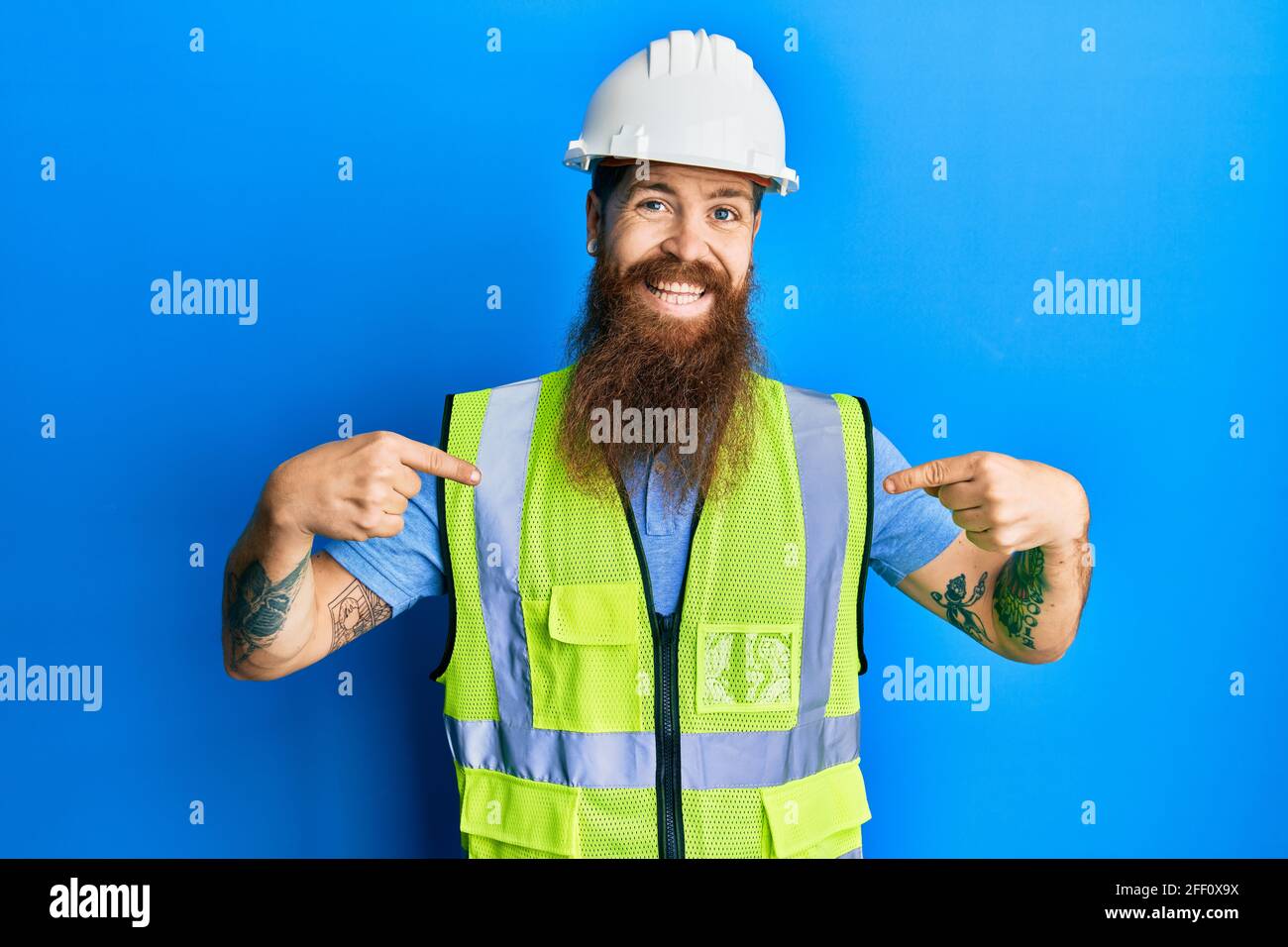 Redhead man with long beard wearing safety helmet and reflective jacket ...