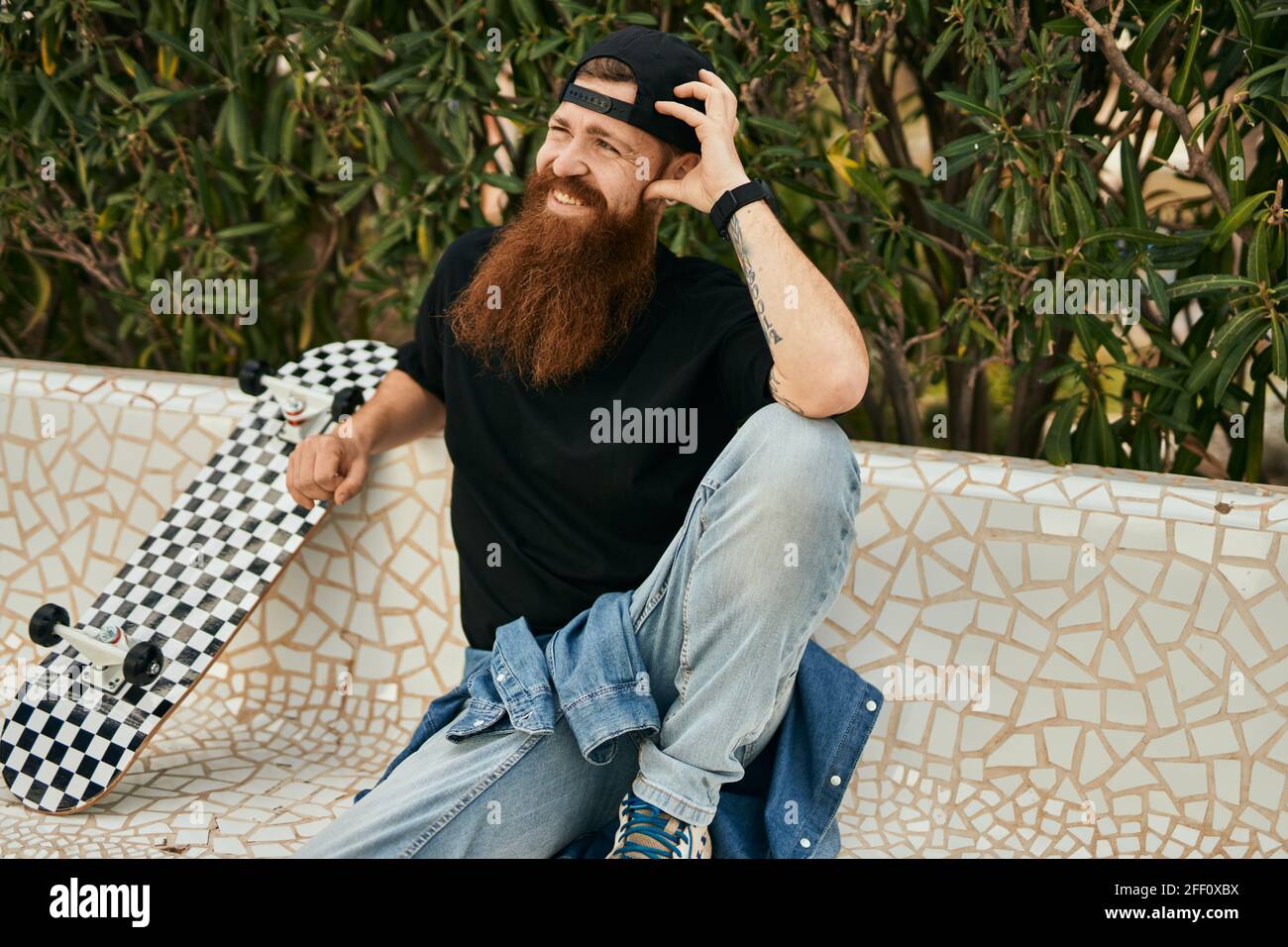 Young irish skater man smiling happy sitting on the bench at the park ...