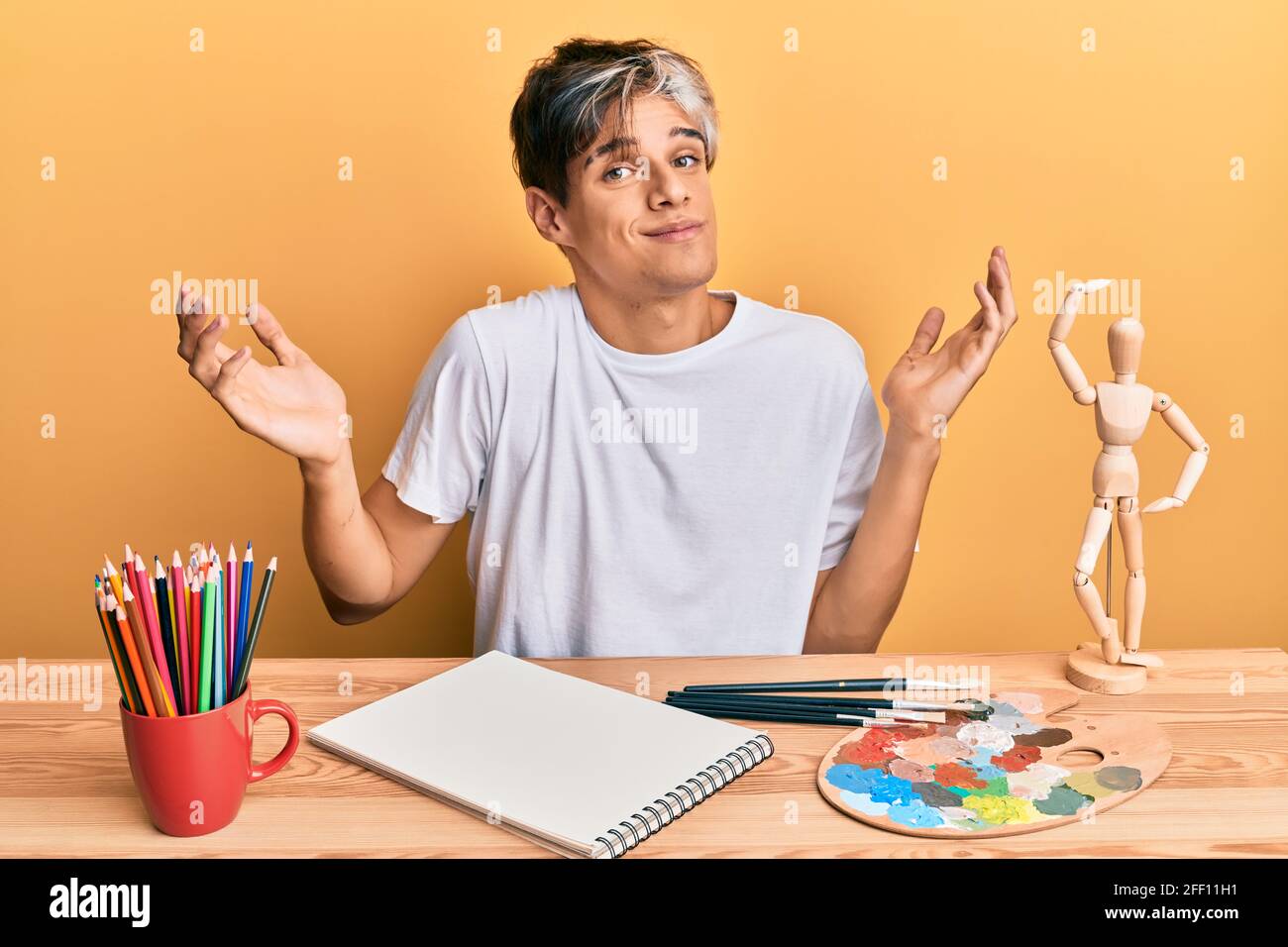 Young hispanic man artist sitting at the studio clueless and confused ...