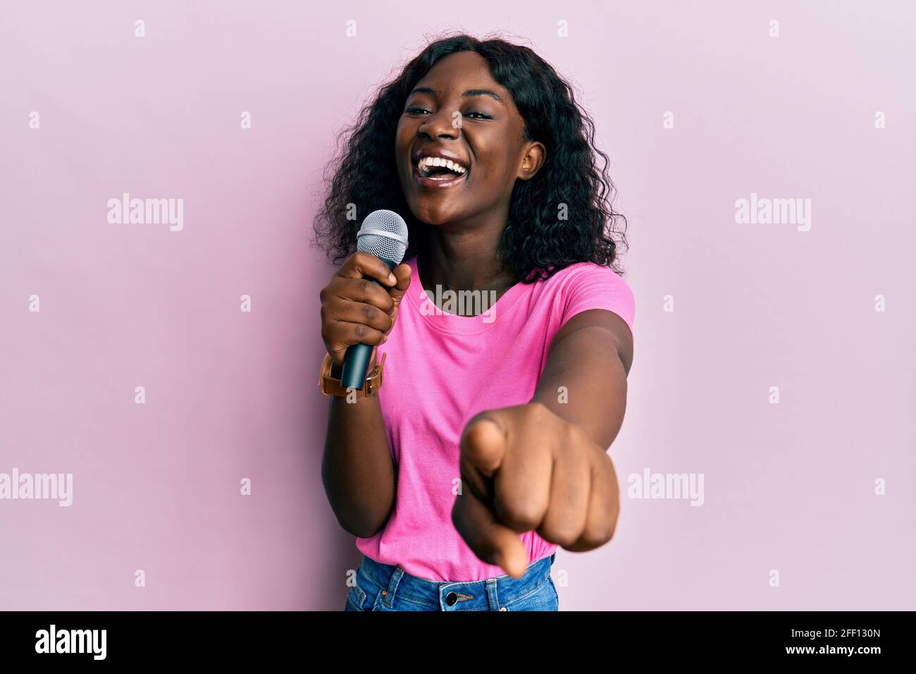 Beautiful african young woman singing song using microphone pointing to ...