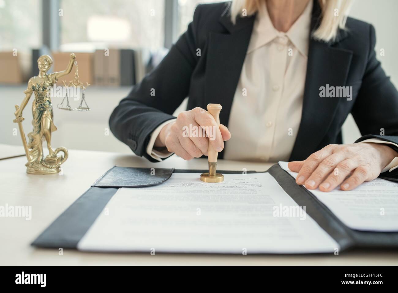 Close-up of unrecognizable female lawyer in black suit sitting at desk ...