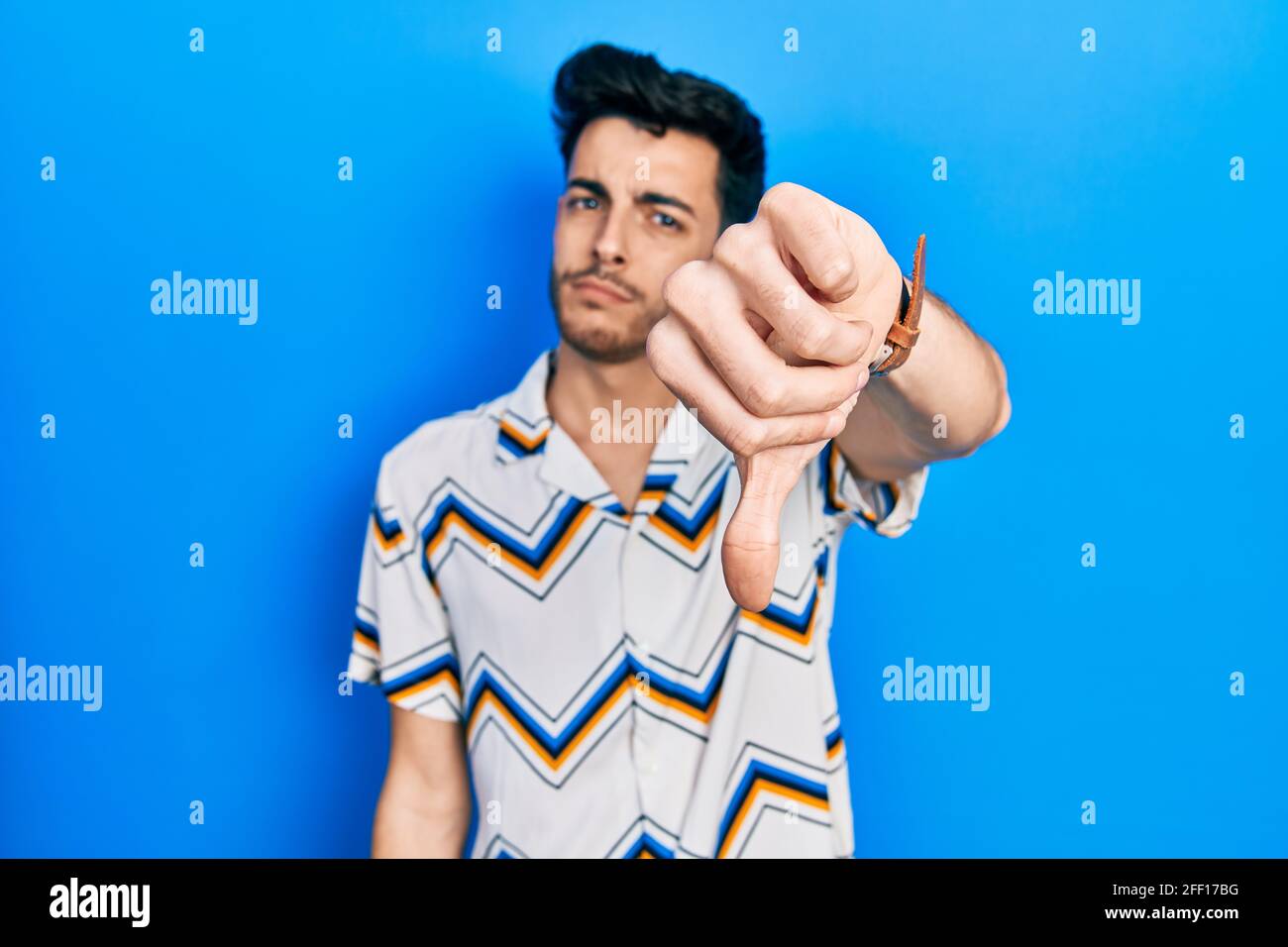 Young hispanic man wearing casual clothes looking unhappy and angry ...
