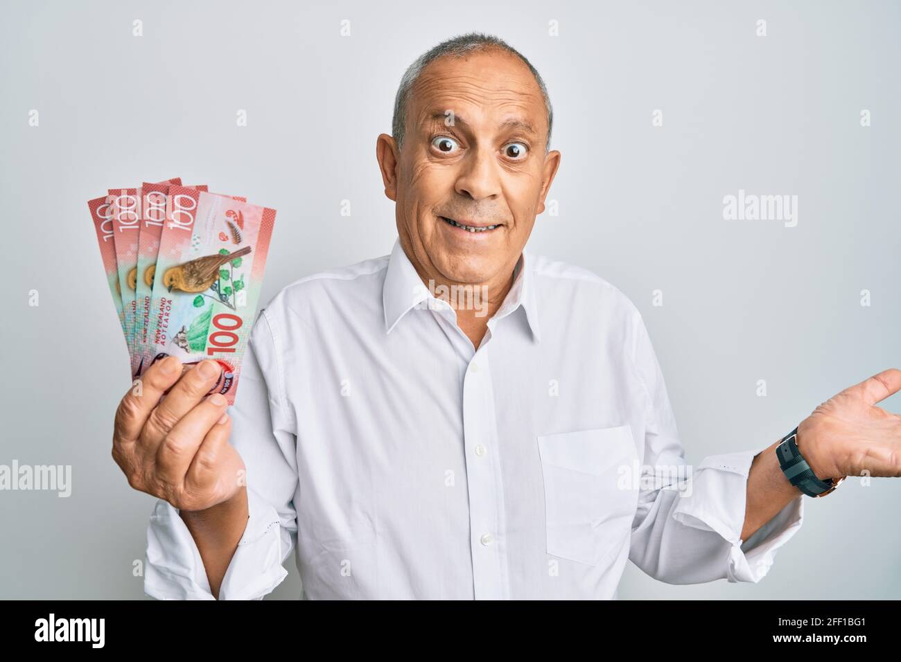 Handsome senior man holding 100 new zealand dollars banknote ...