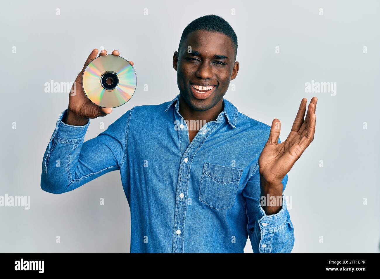 Young african american man holding compact disc celebrating victory ...