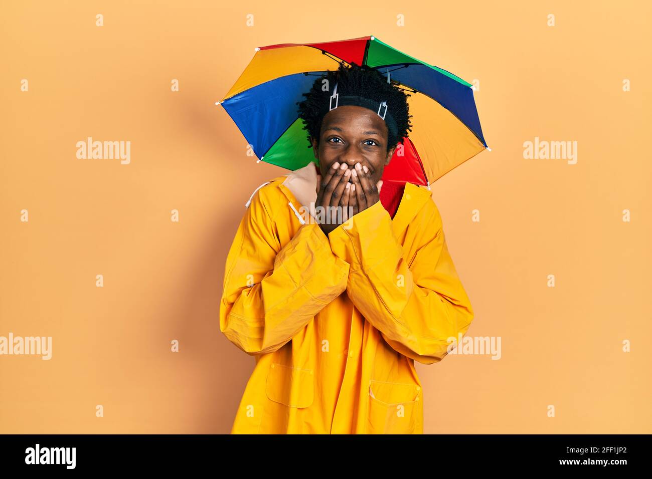 Young african american man wearing yellow raincoat laughing and ...