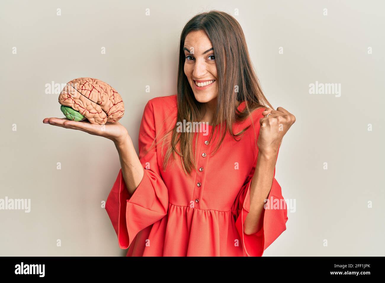 Young beautiful woman holding brain screaming proud, celebrating ...