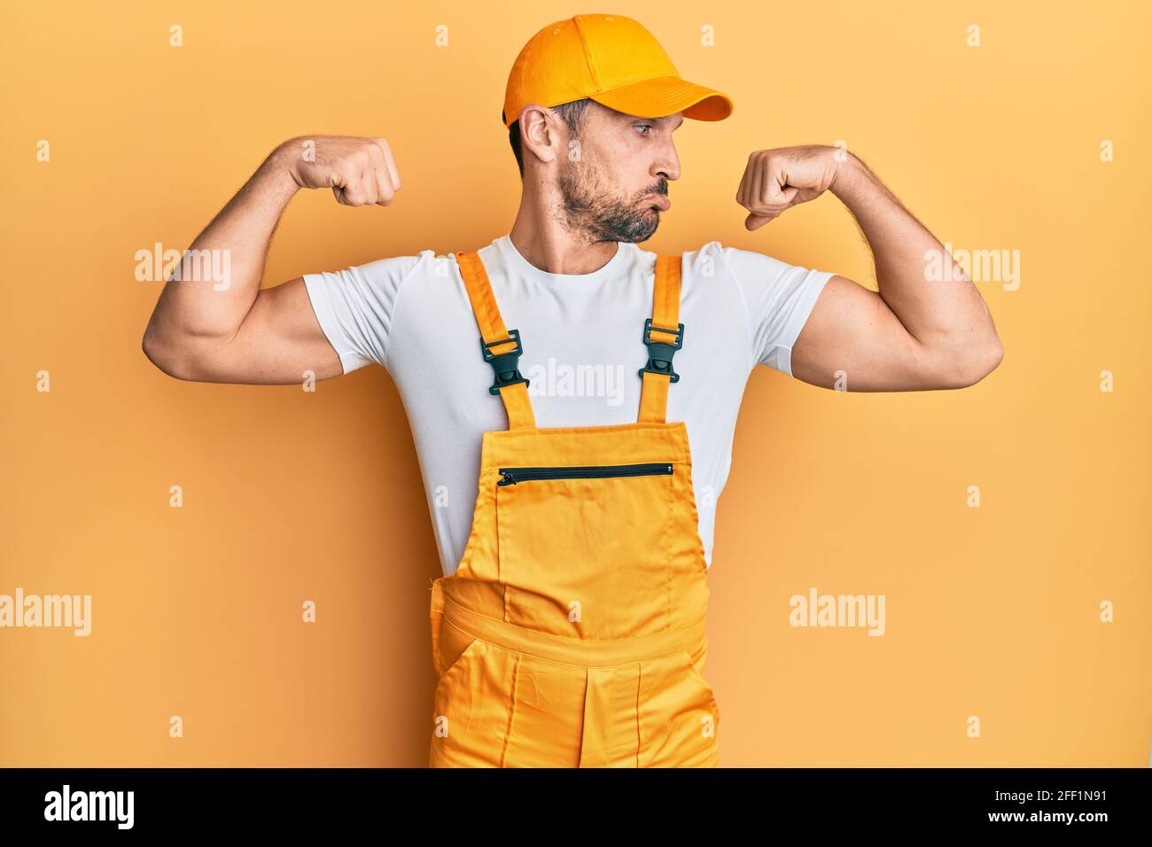 Young handsome man wearing handyman uniform over yellow background ...