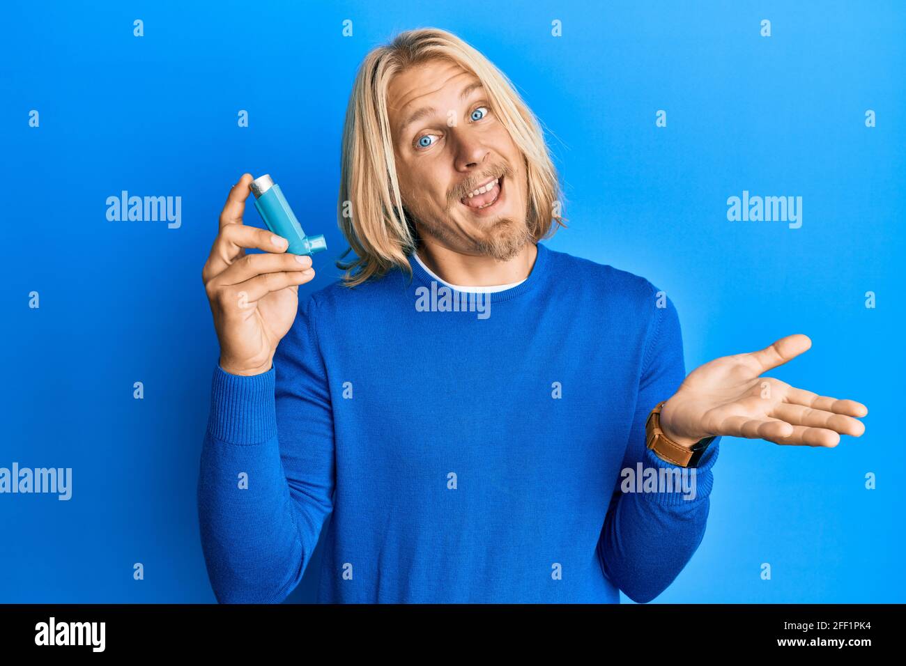 Caucasian young man with long hair holding medical asthma inhaler ...