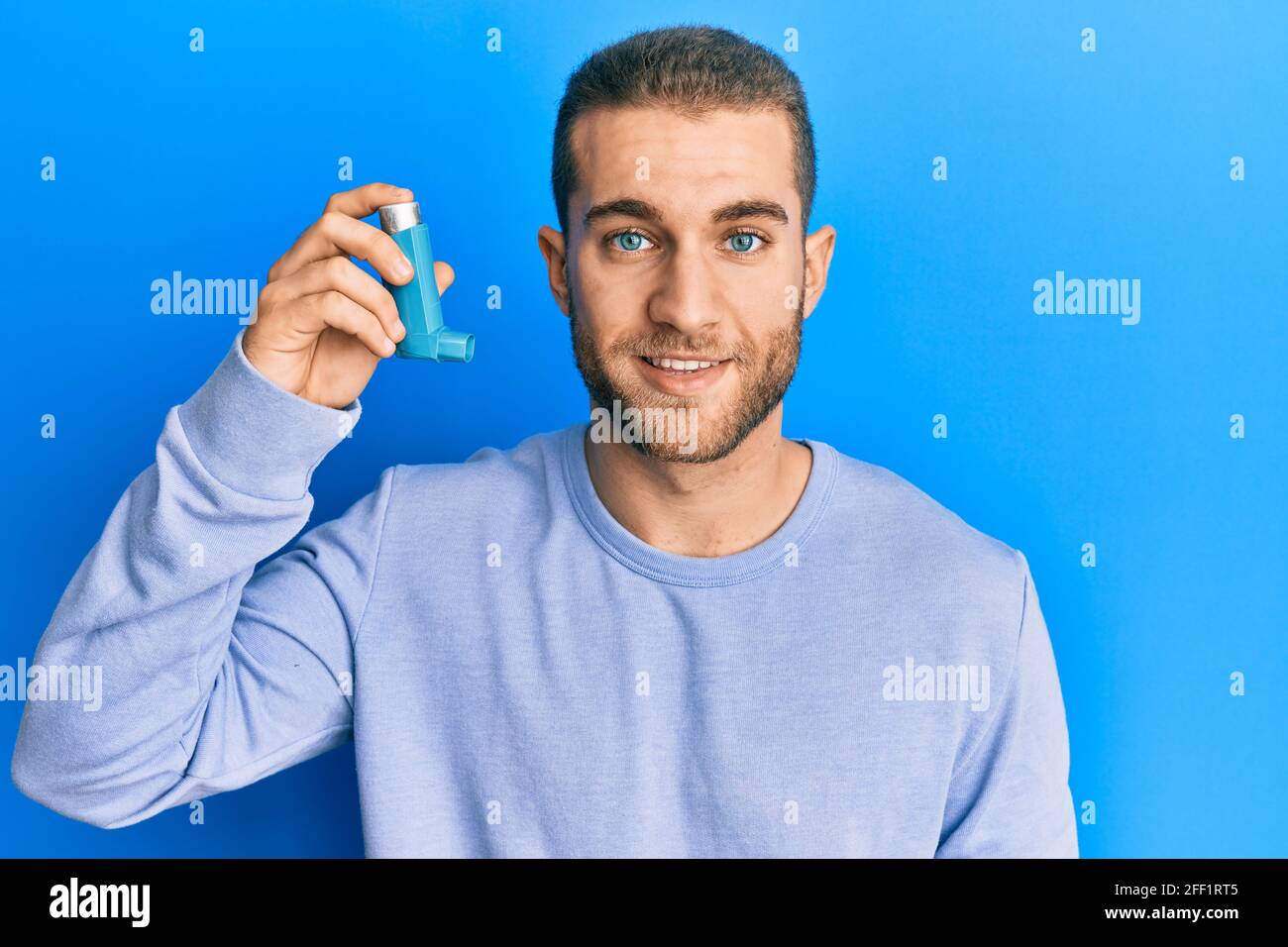 Young caucasian man holding medical asthma inhaler looking positive and ...