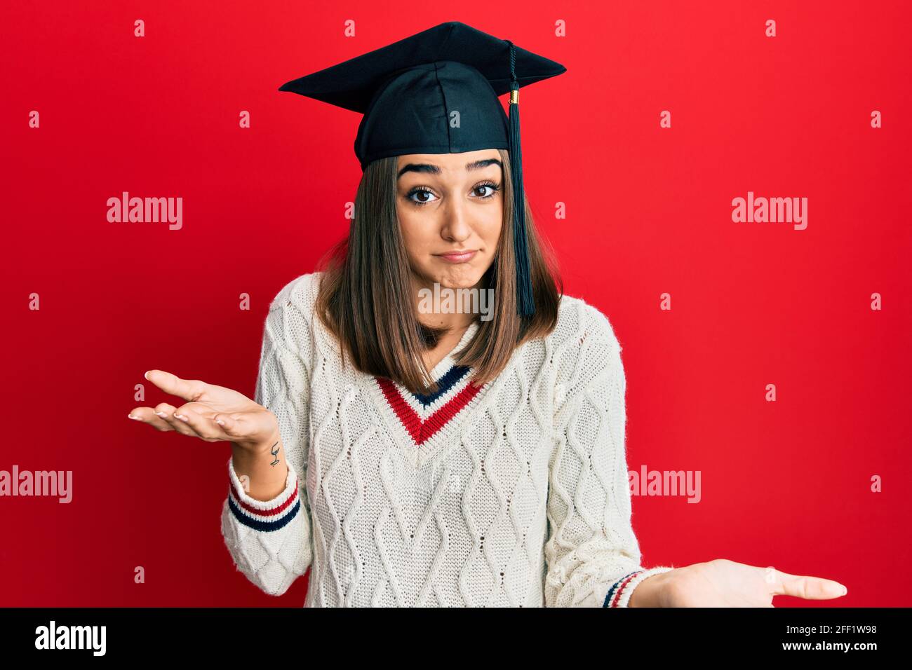 Young brunette girl wearing graduation cap clueless and confused ...