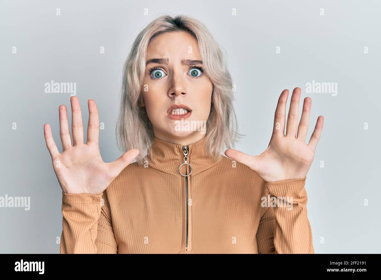 Young blonde girl wearing casual clothes afraid and terrified with fear ...