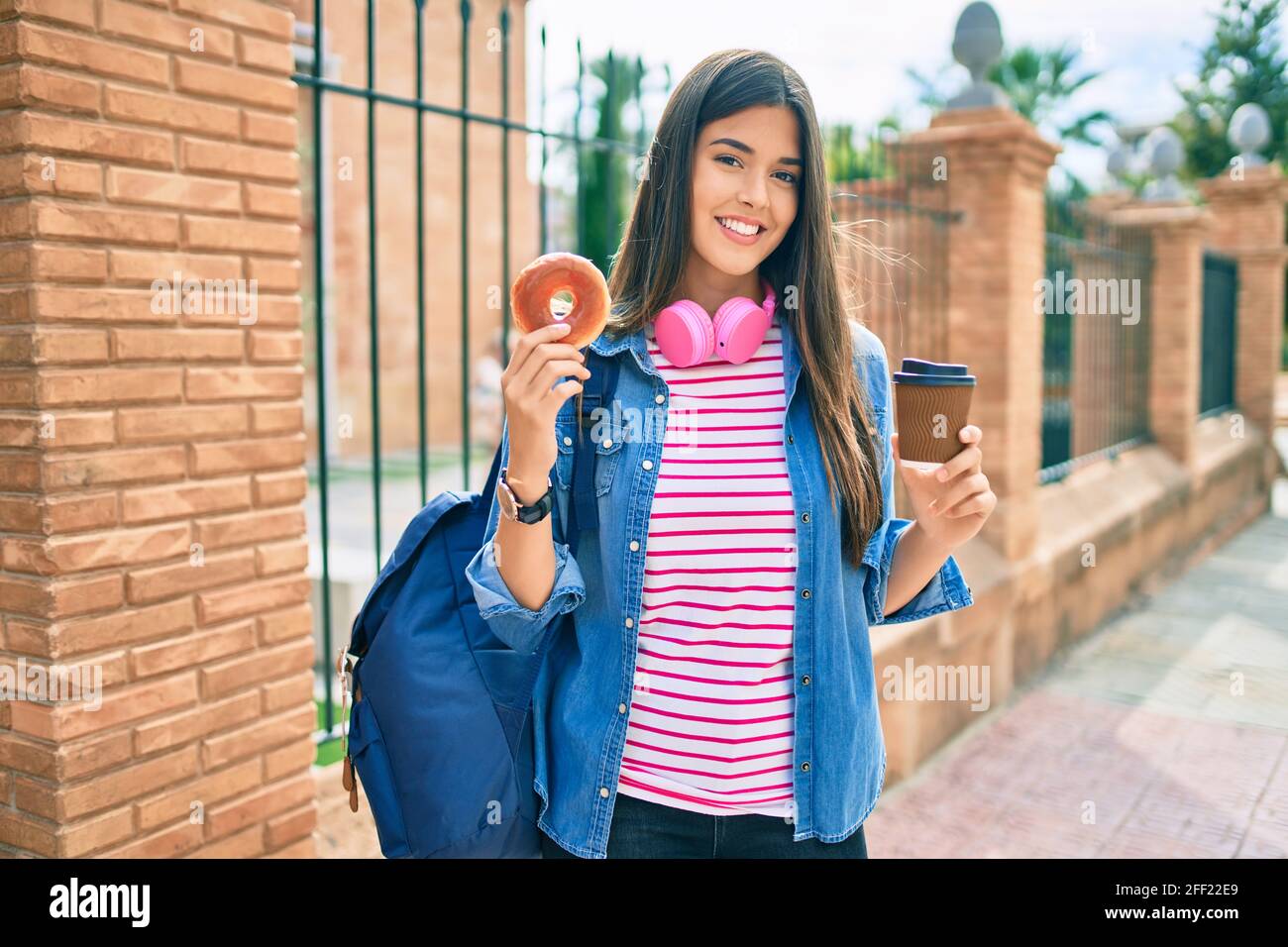 Young hispanic student girl smiling happy having breakfast at the city ...