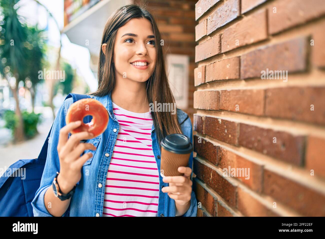 Young hispanic student girl smiling happy having breakfast at the city ...