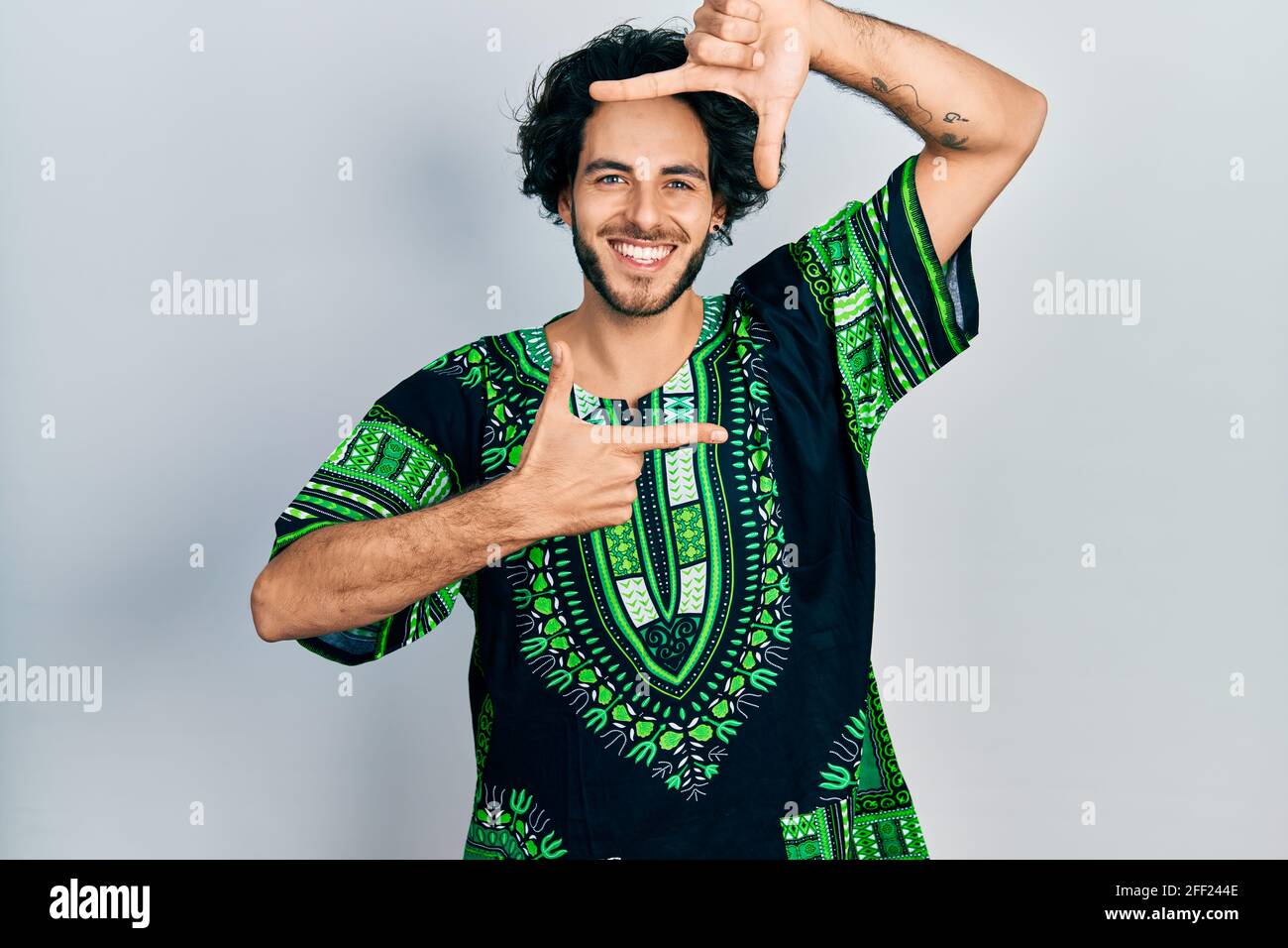Handsome hispanic man wearing traditional african clothes smiling ...