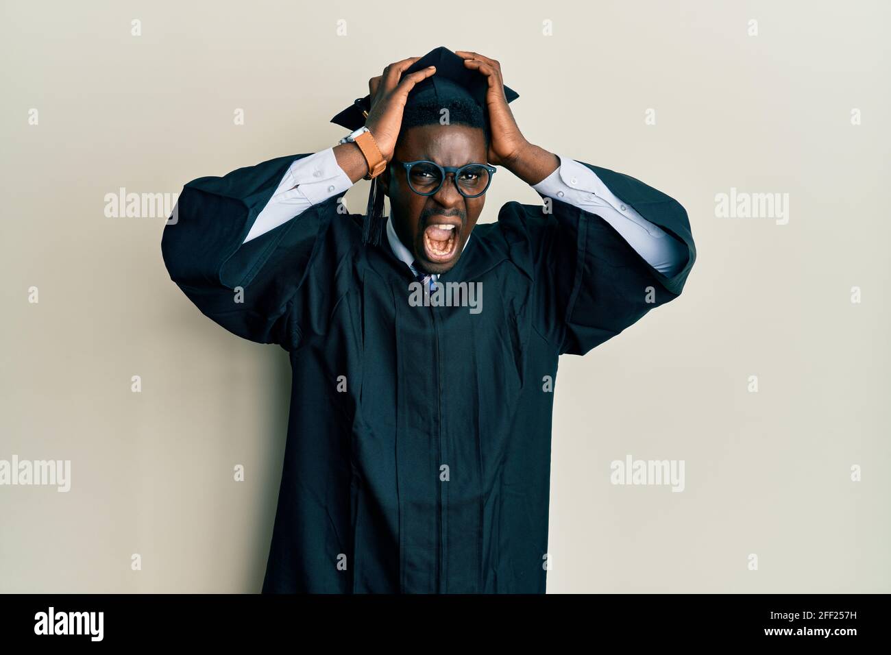 Handsome black man wearing graduation cap and ceremony robe crazy and ...