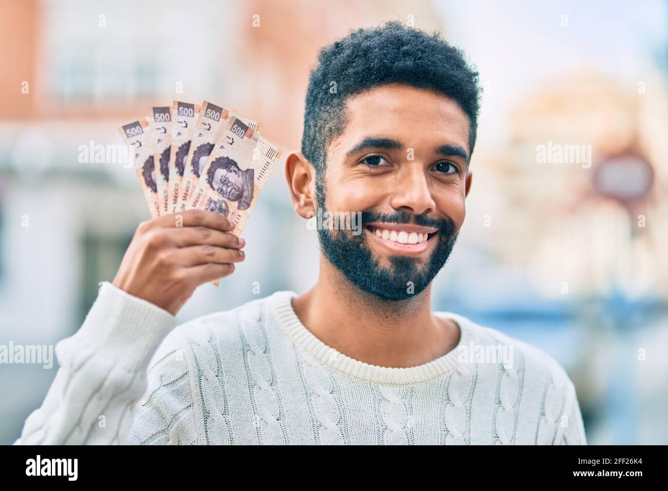Young african american man smiling happy holding mexican 500 pesos ...