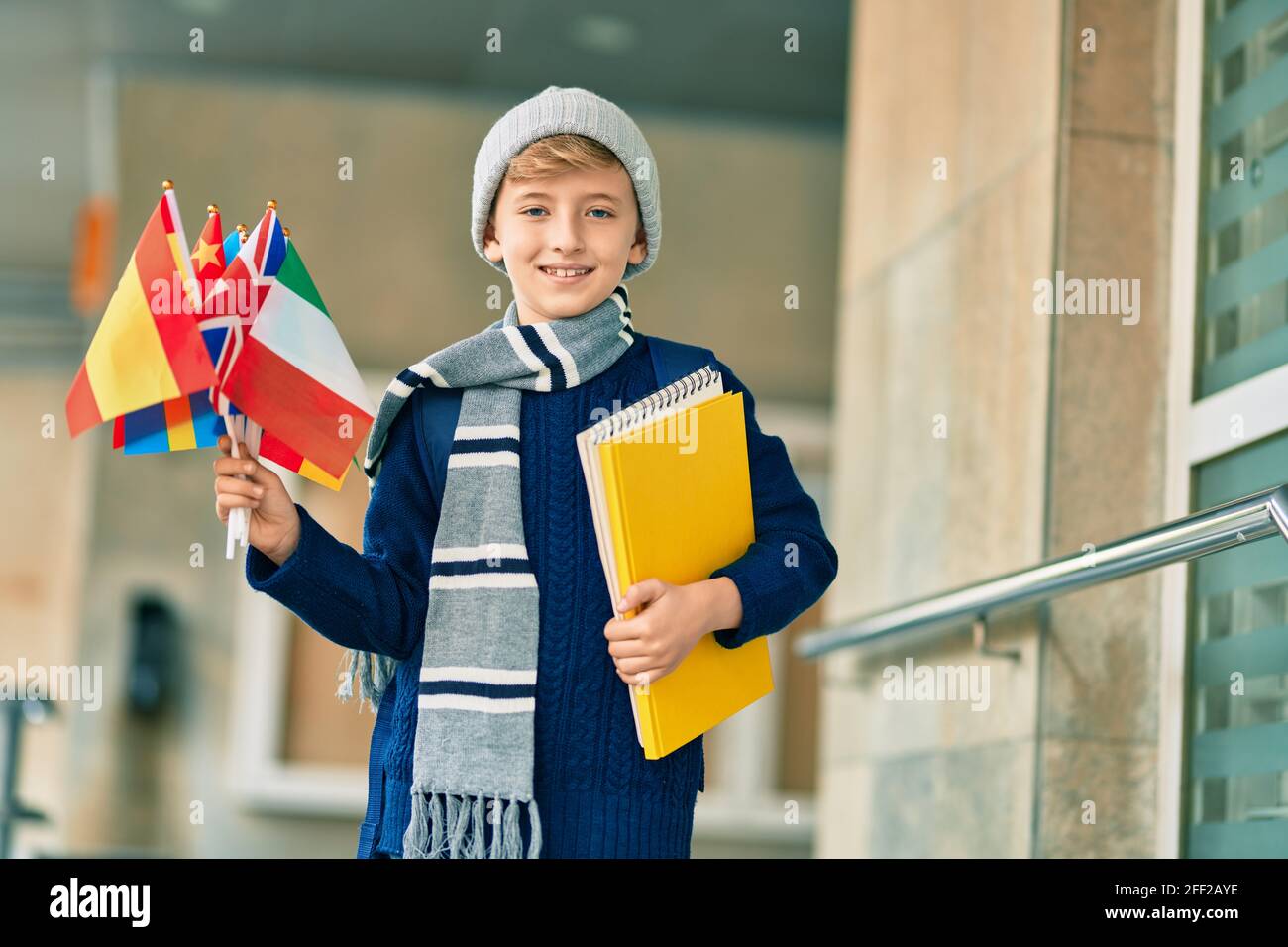 Adorable blond student kid smiling happy holding flags of different ...