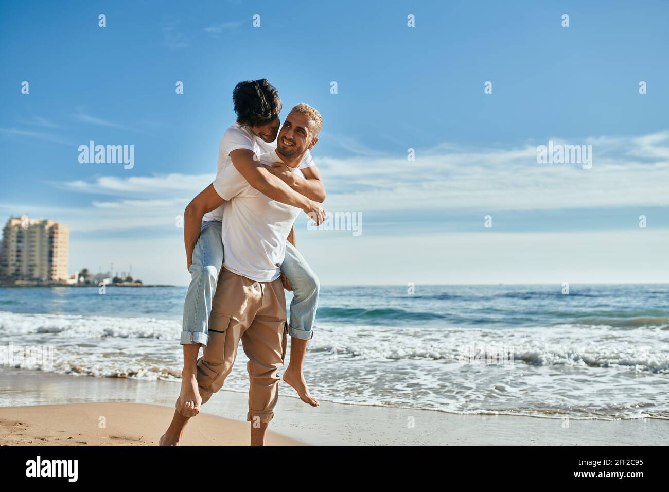 Lovely gay couple on piggyback ride at the beach Stock Photo - Alamy