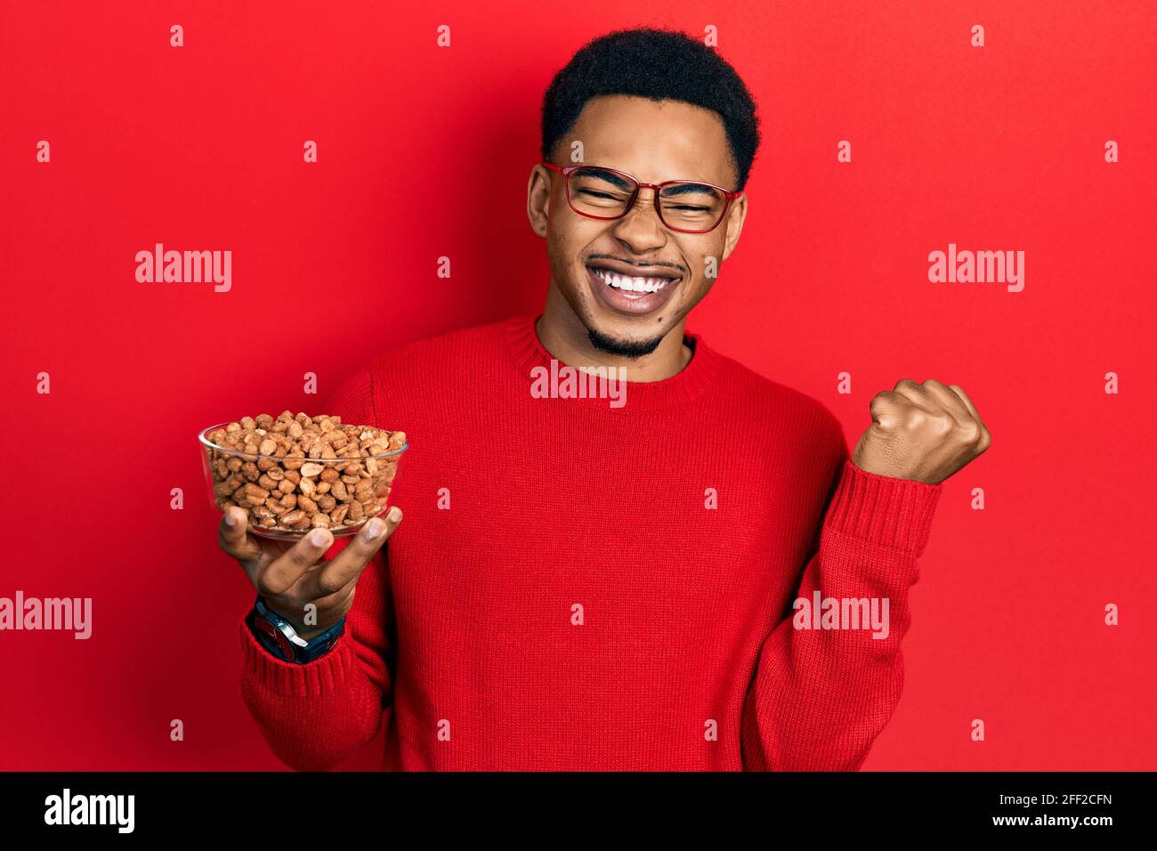 Young african american man holding peanuts screaming proud, celebrating ...