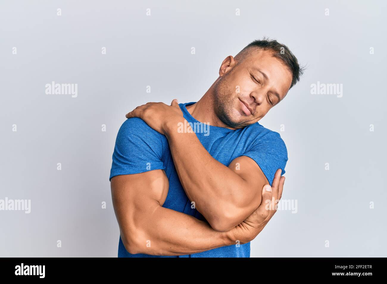 Handsome muscle man wearing casual clothes hugging oneself happy and ...