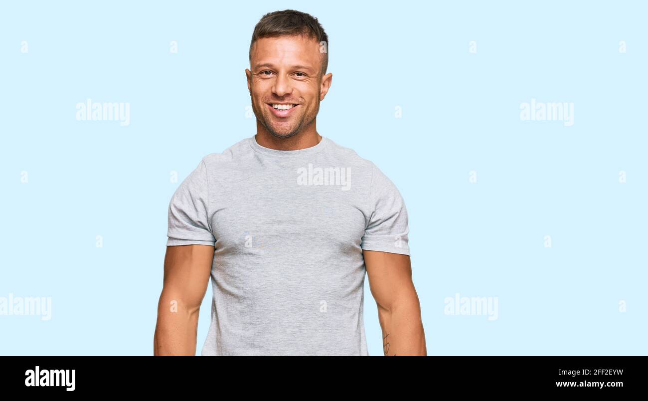 Handsome muscle man wearing casual grey tshirt looking positive and ...