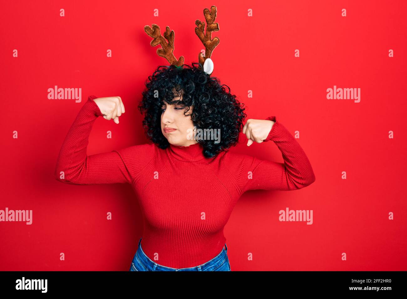 Young middle east woman wearing cute christmas reindeer horns showing ...
