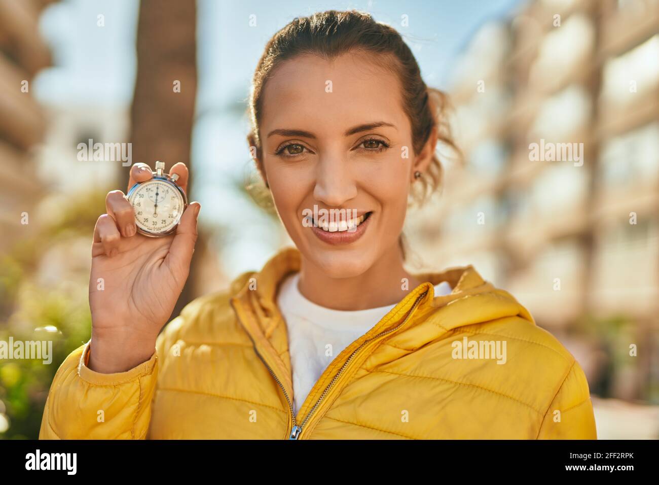 Young hispanic girl smiling happy holding stopwatch at the city Stock ...