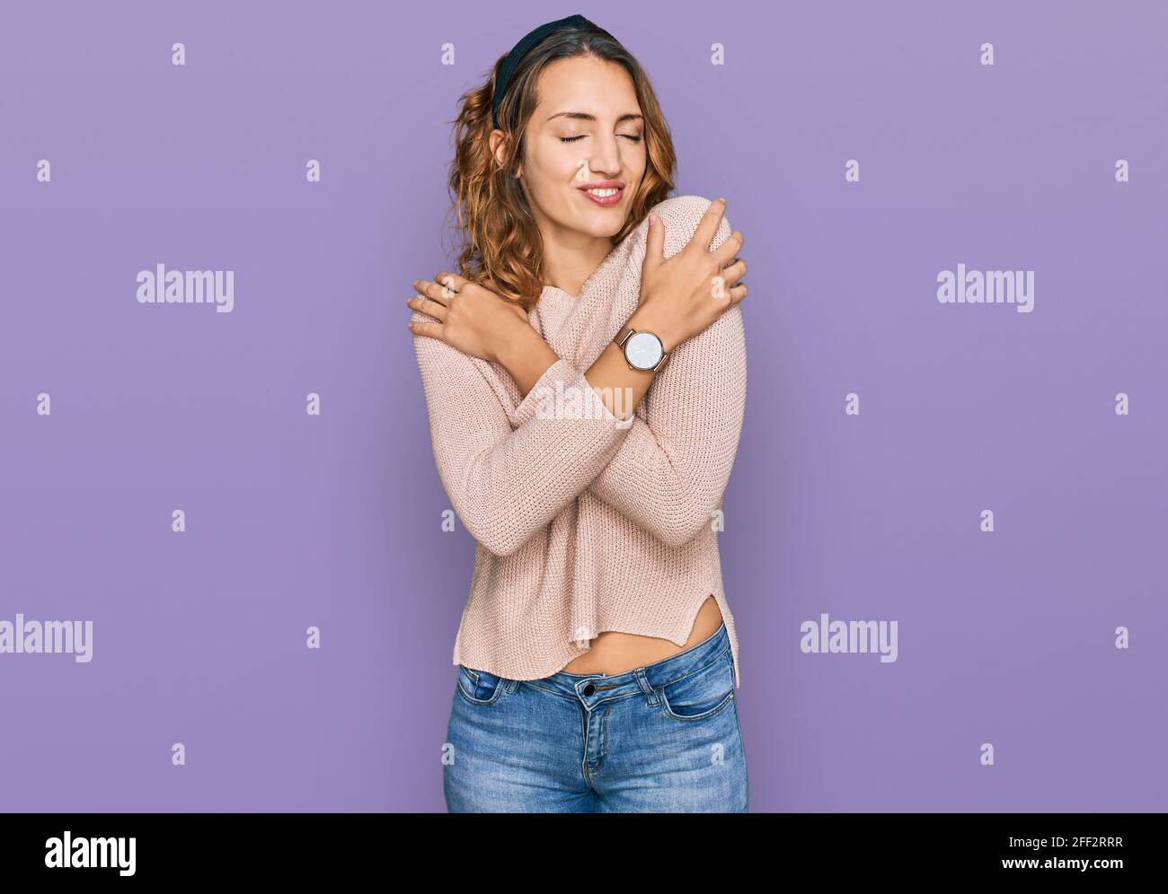 Beautiful young caucasian woman wearing casual sweater hugging oneself ...