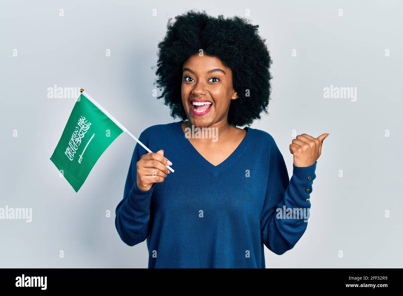 Young african american woman holding kingdom of saudi arabia flag ...