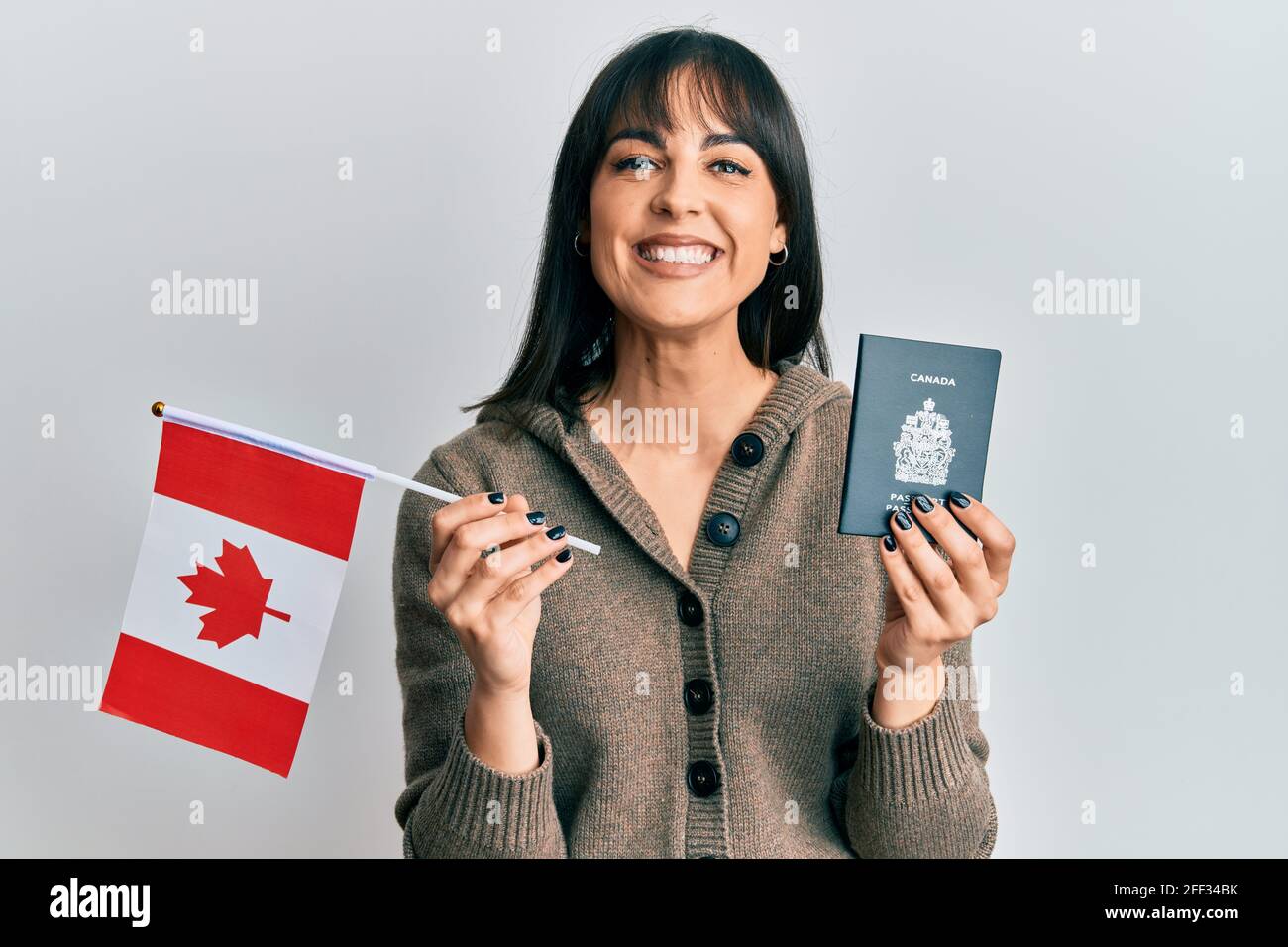 Young hispanic woman holding canada flag and passport smiling with a ...