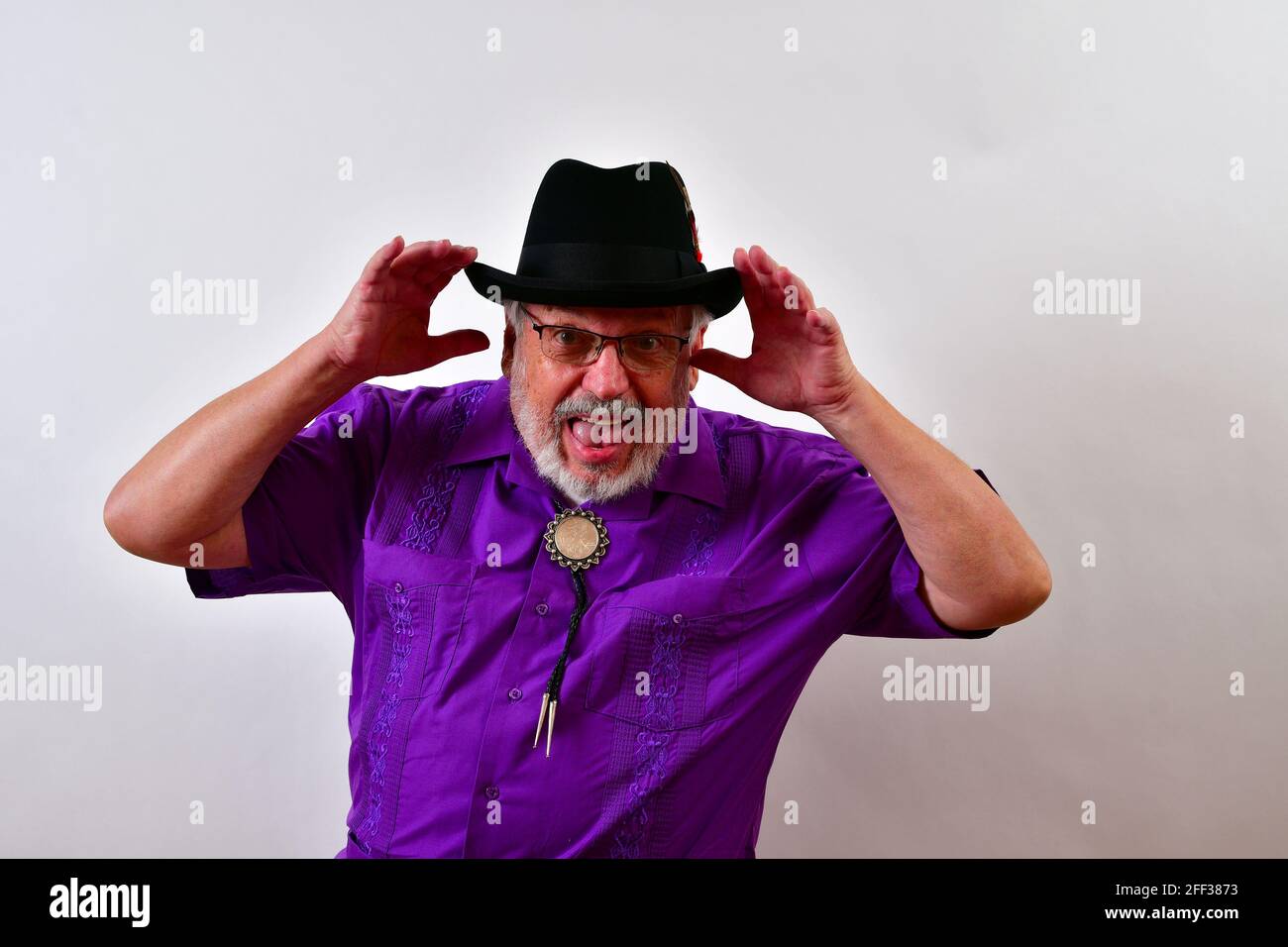 Smartly dressed elderly gentleman making a crazy face and hand gestures ...