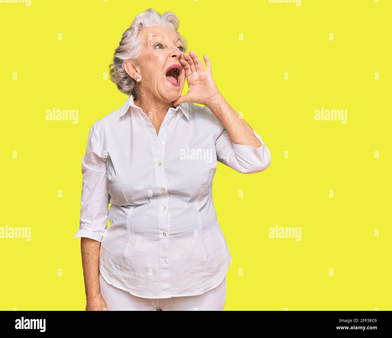 Senior grey-haired woman wearing casual clothes shouting and screaming ...
