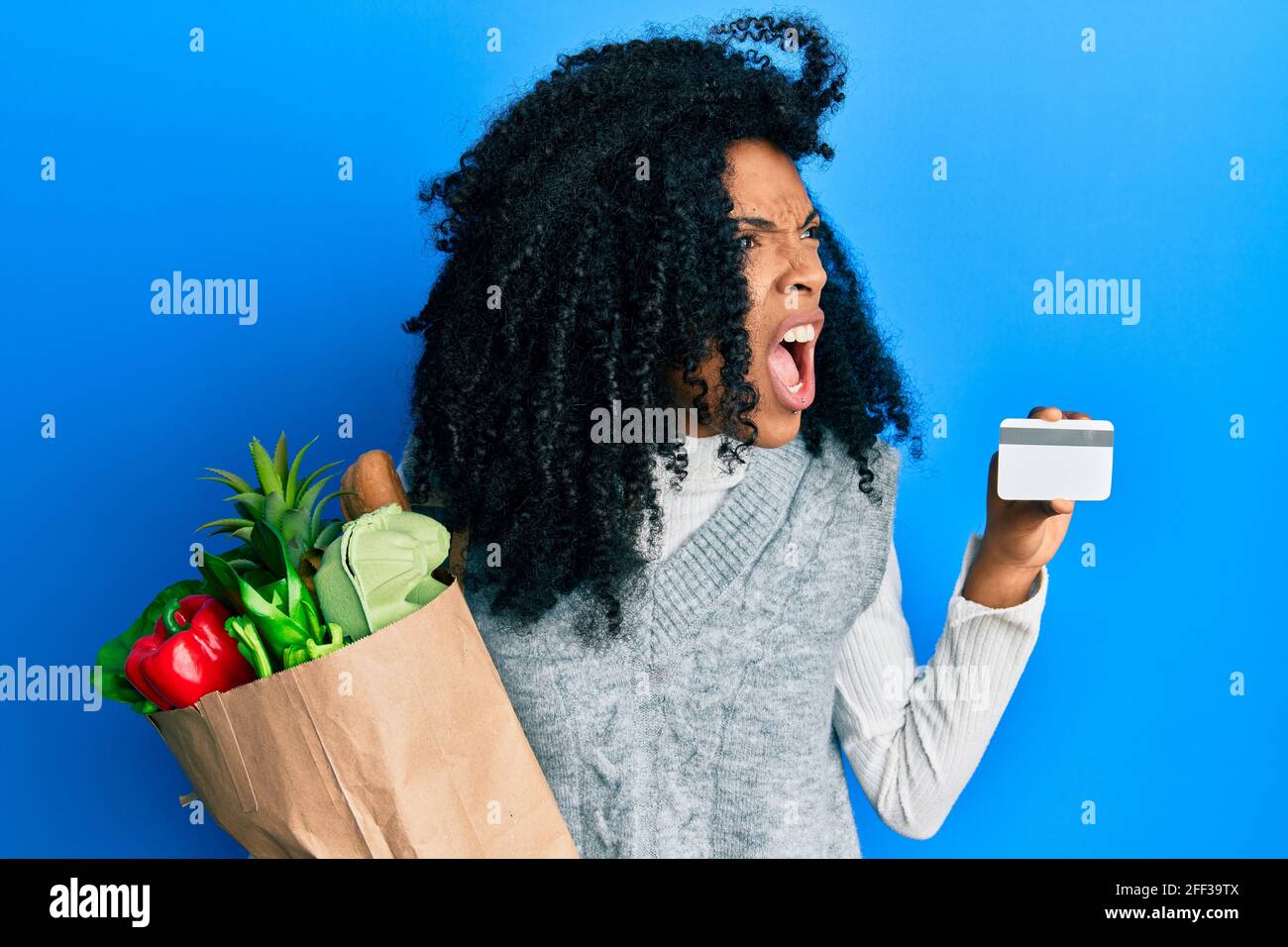 African american woman with afro hair holding groceries and credit card ...