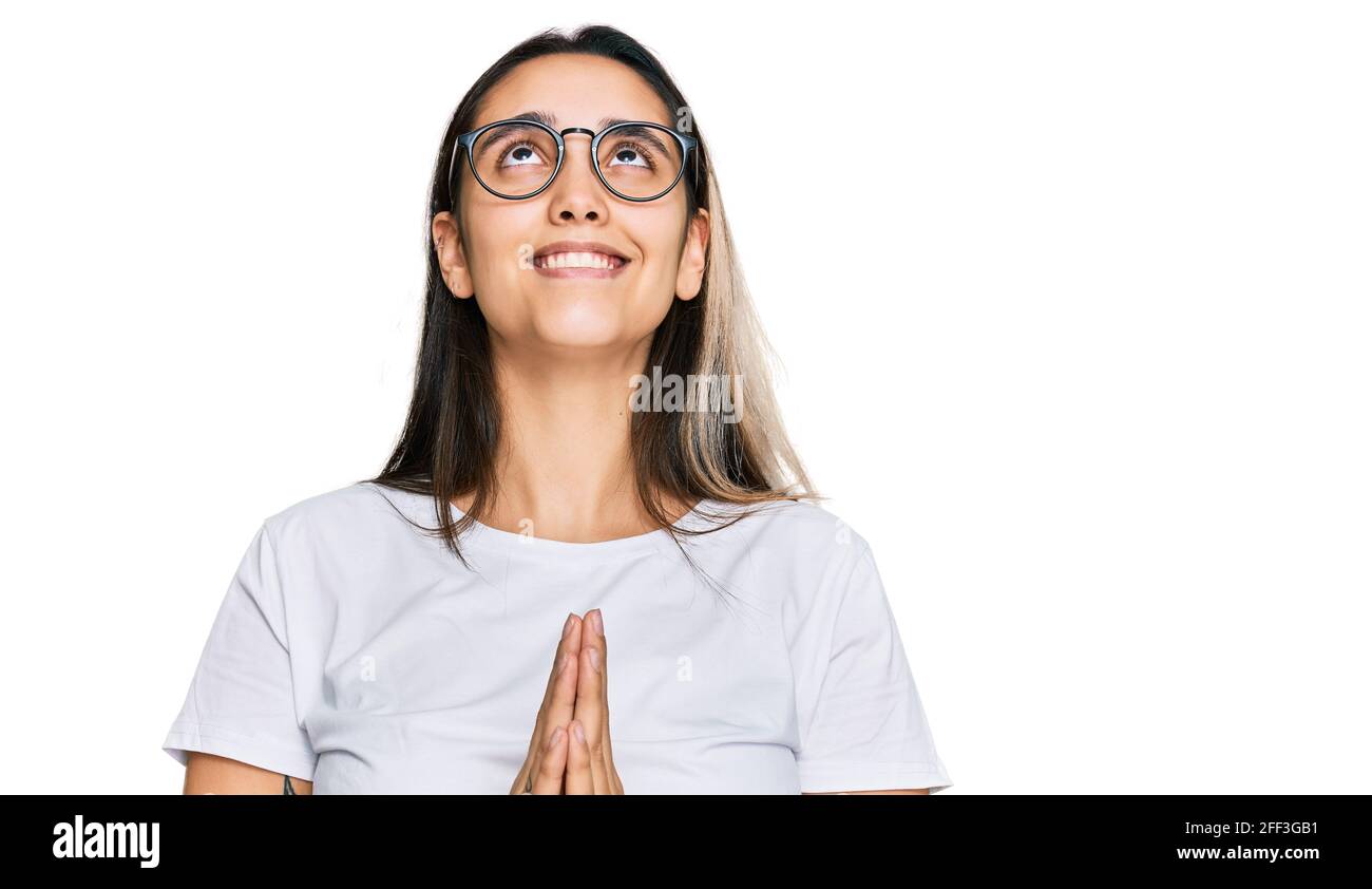 Young hispanic woman wearing casual white t shirt begging and praying ...