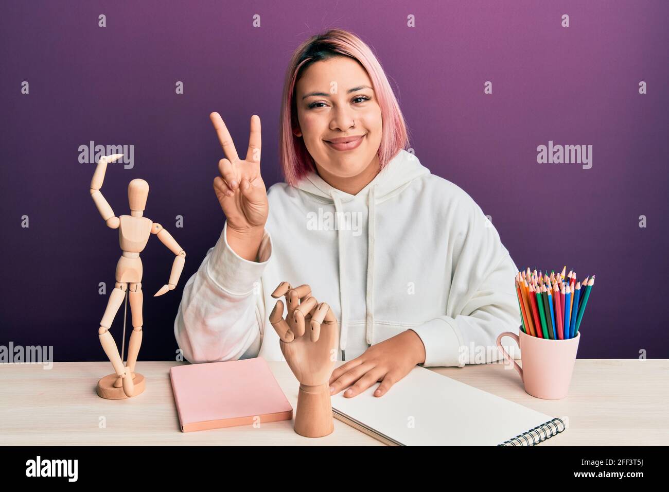 Hispanic woman with pink hair sitting at art studio smiling with happy ...