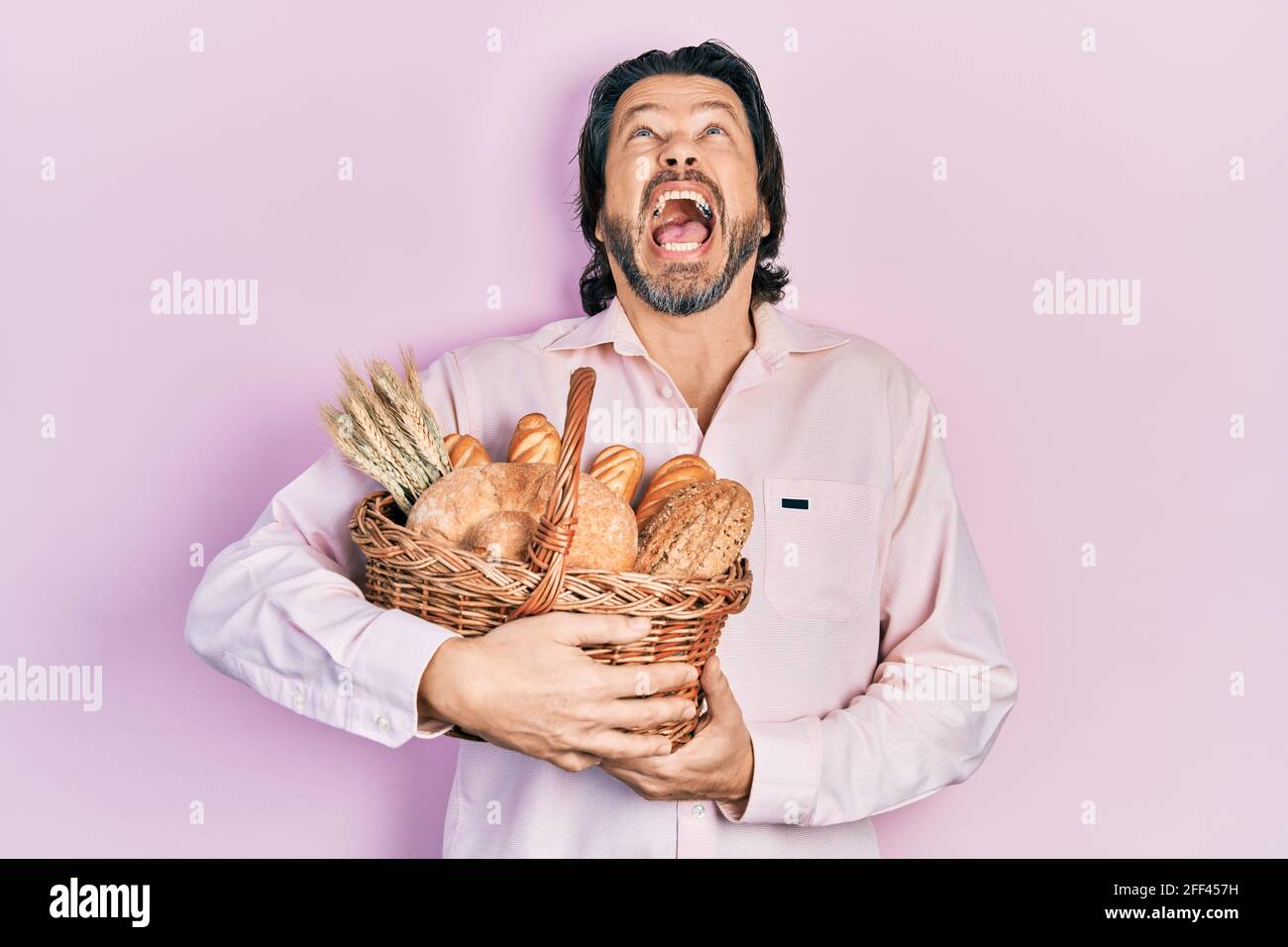 Middle age caucasian man holding wicker basket with bread angry and mad ...