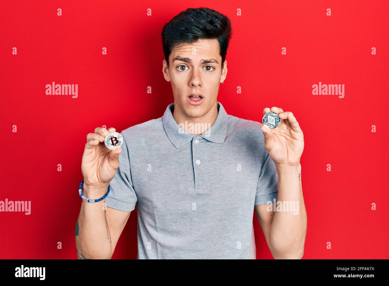 Young hispanic man holding virtual currency ethereum coin and bitcoin ...
