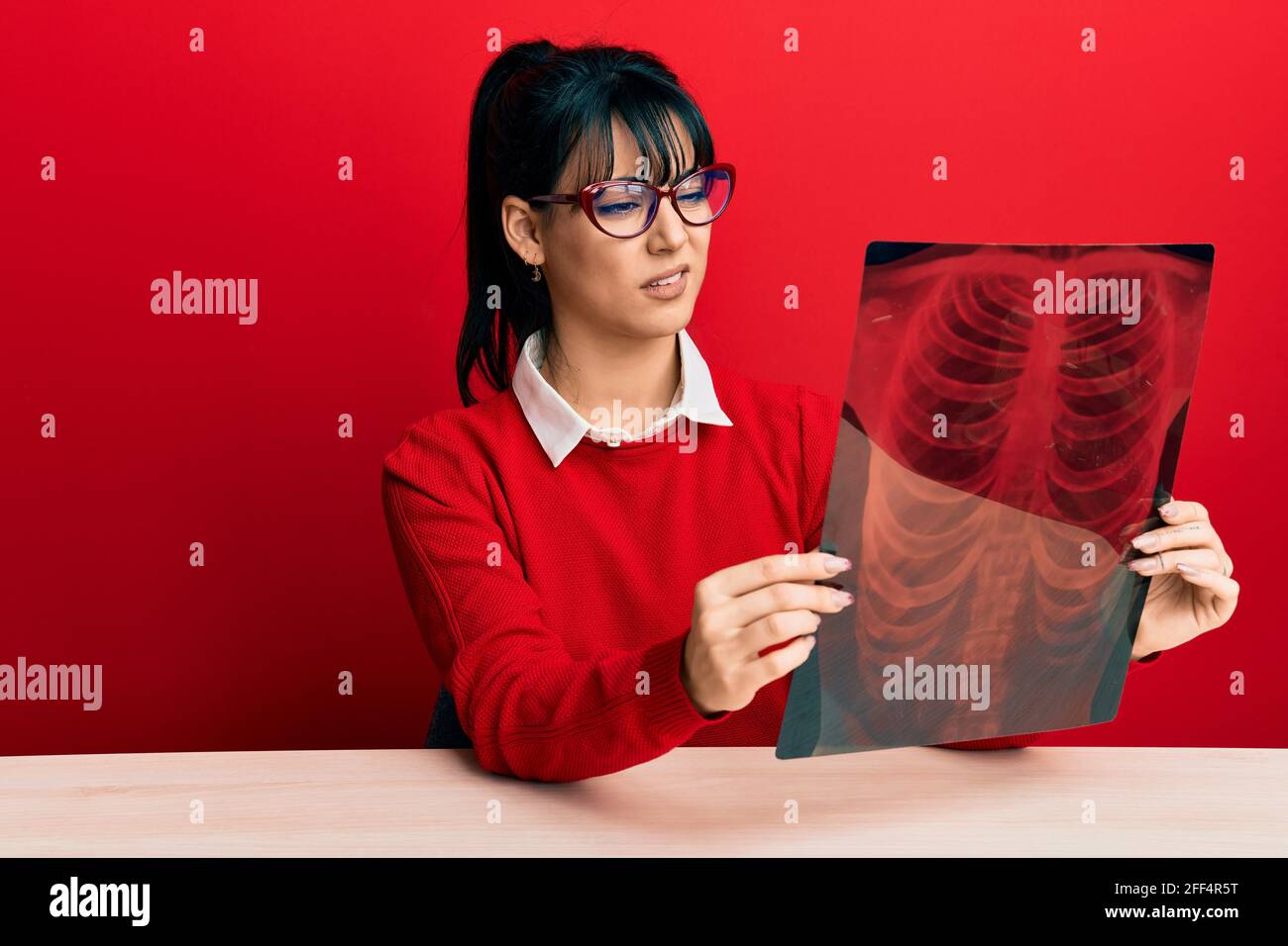 Young brunette woman with bangs holding chest radiography clueless and ...