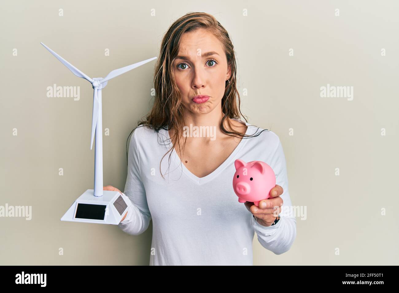 Young blonde woman holding solar windmill for renewable electricity and ...