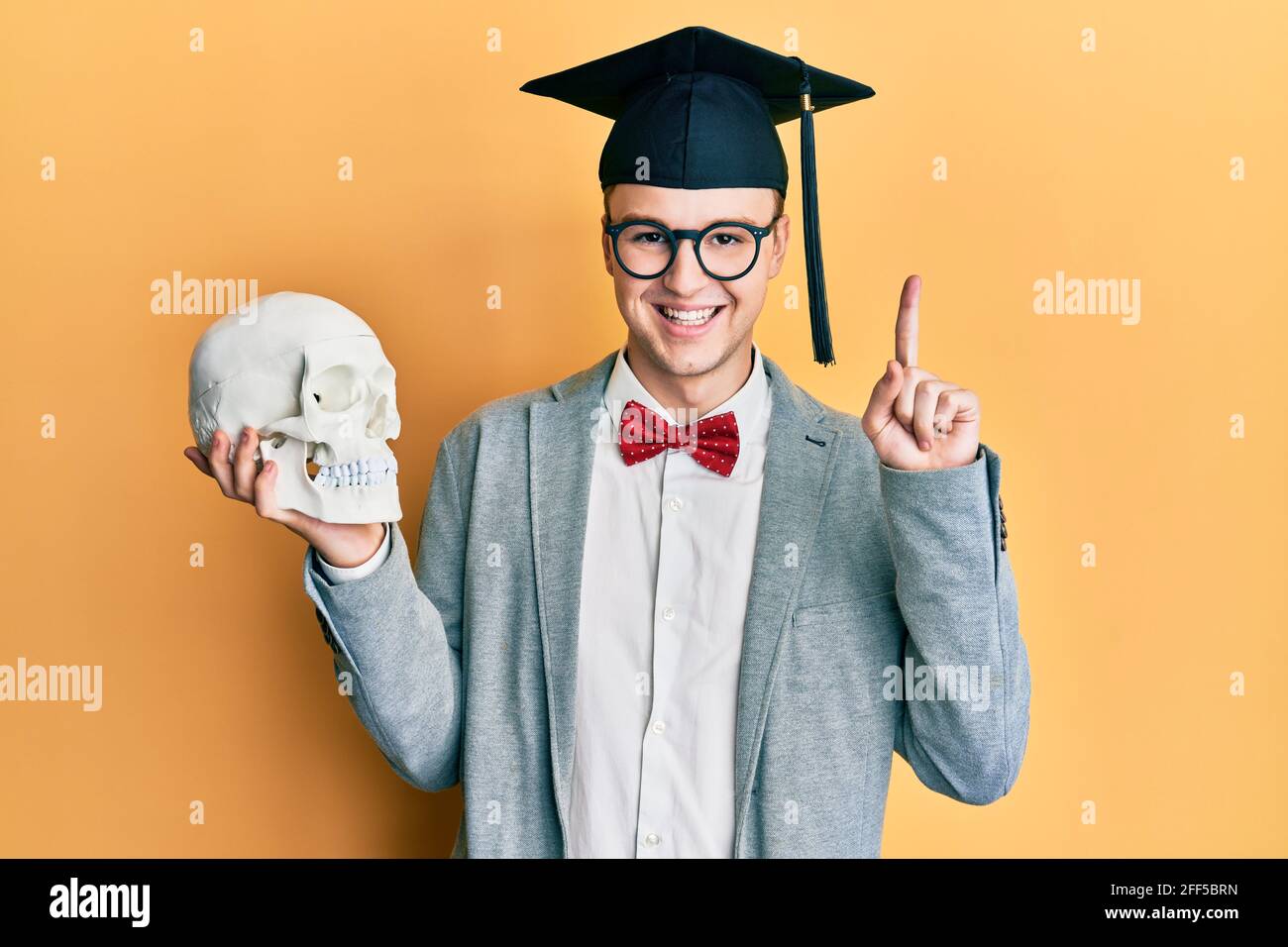 Young caucasian nerd man wearing glasses and graduation cap holding ...
