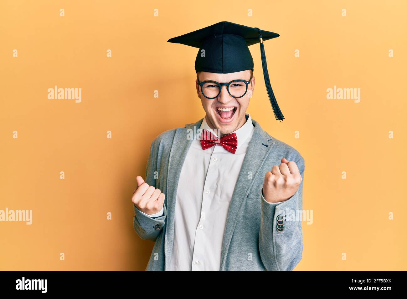 Young caucasian nerd man wearing glasses and graduation cap celebrating ...