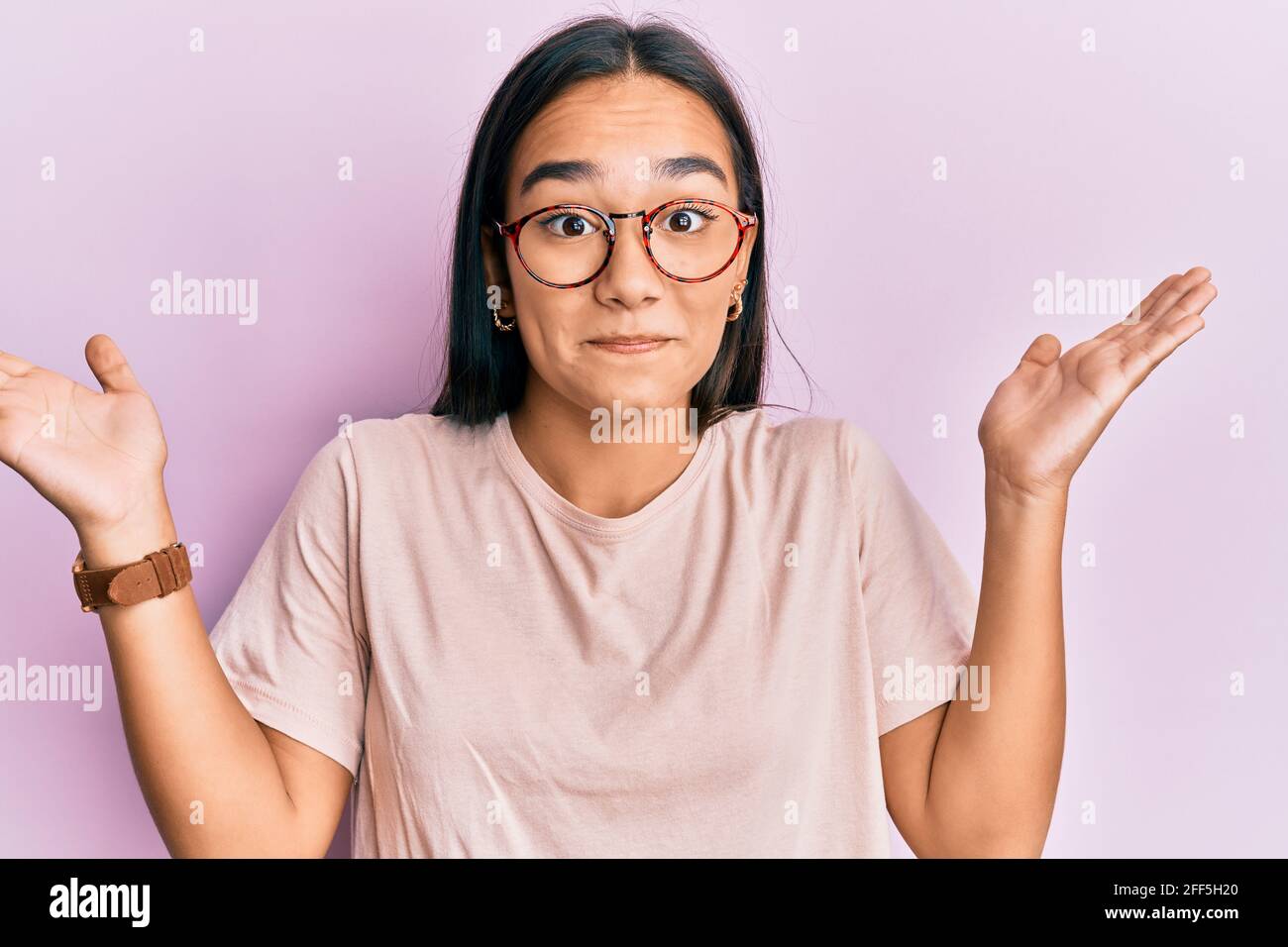 Young asian woman wearing casual clothes and glasses clueless and ...