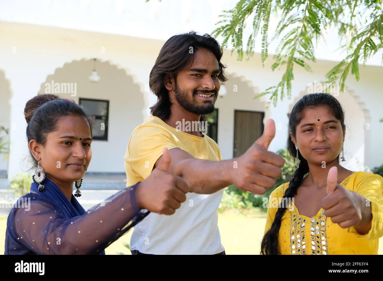 Group of young Indian people showing thumbs up while standing outdoors ...