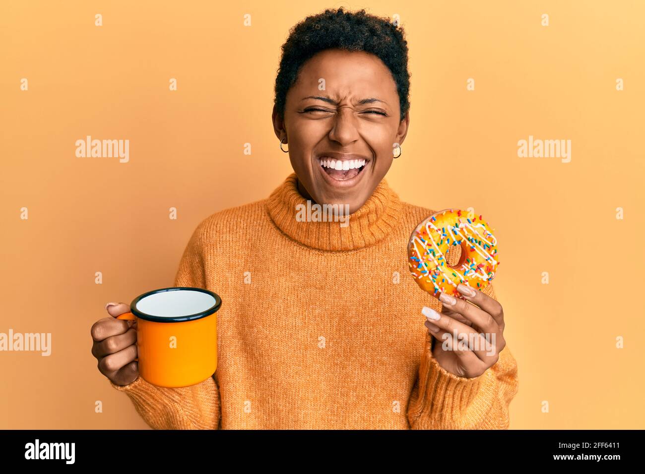 Young african american girl eating doughnut and drinking coffee smiling ...