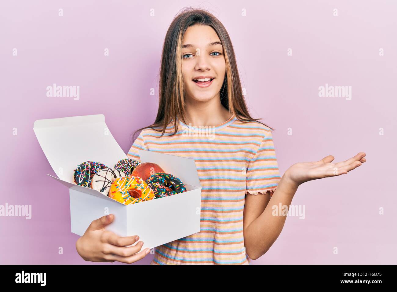 Young brunette girl holding tasty colorful doughnuts celebrating ...